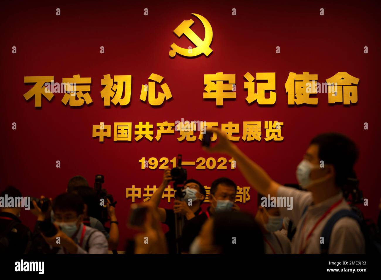 Visitors and journalists take photos near a display with the slogan ...