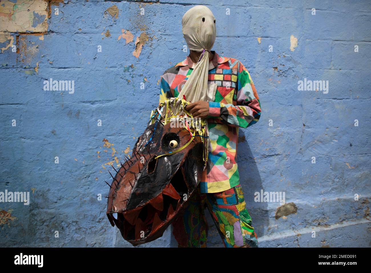 A man dressed in a devil costume holds his mask during a celebration ...