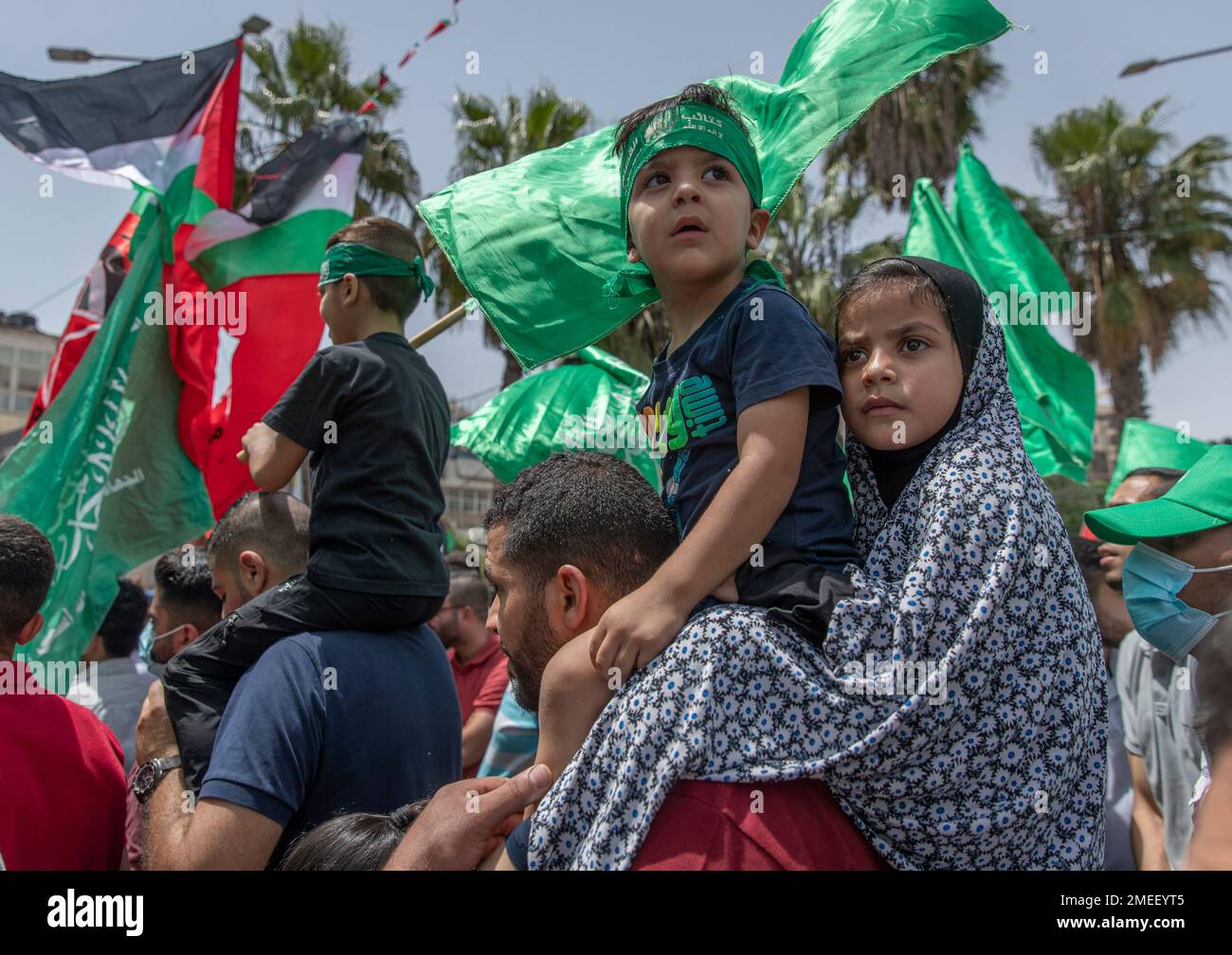 Palestinians carry their children on shoulders and wave Hamas green ...