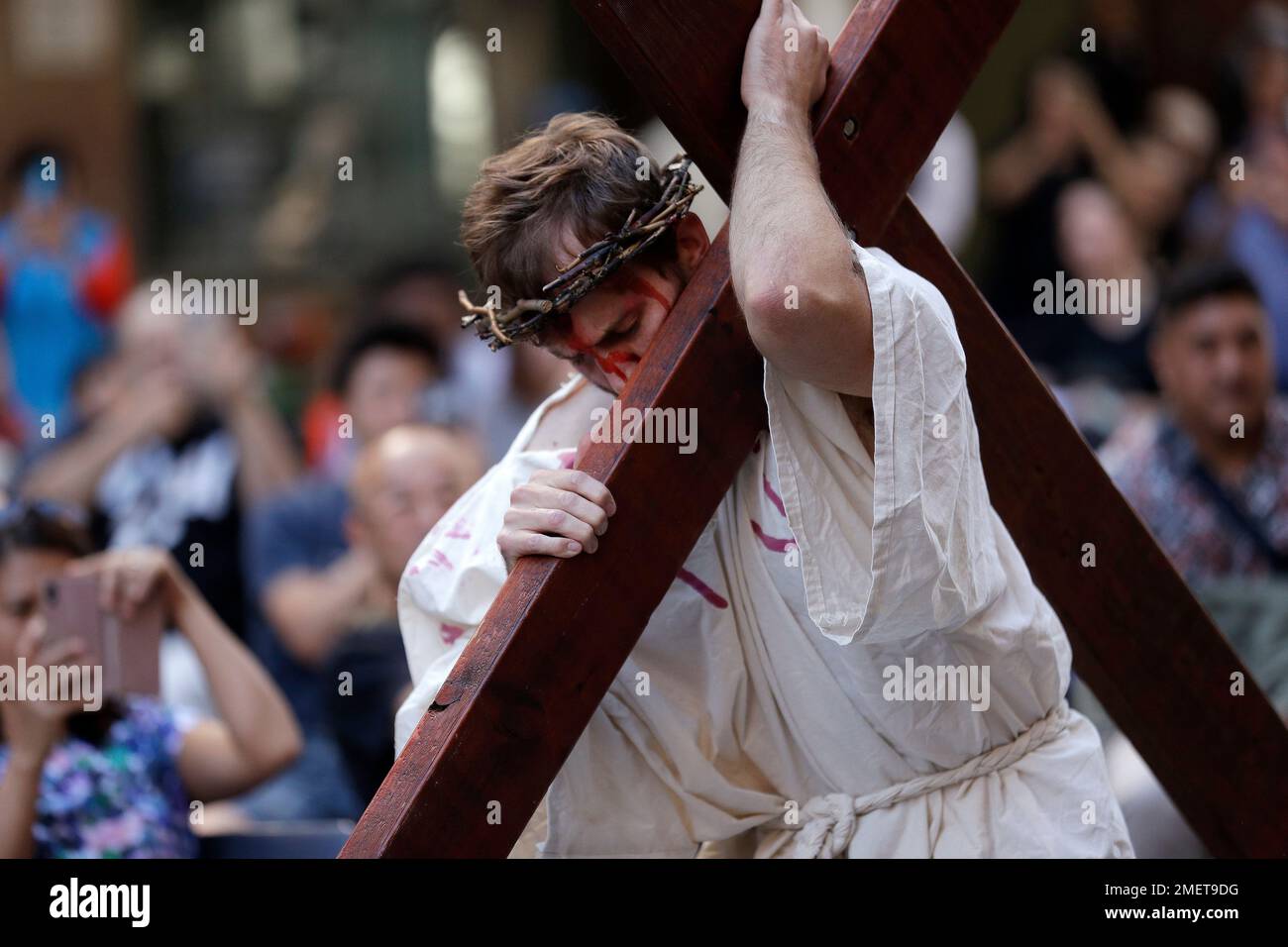Actor Timothy Watkins carries a cross during his portrayal of Jesus ...