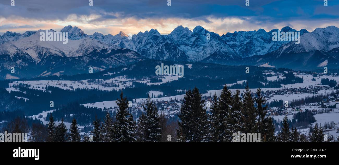 Das Foto zeigt das Tatra-Gebirge zur goldenen Stunde, die Berge sind schneebedeckt und im ...