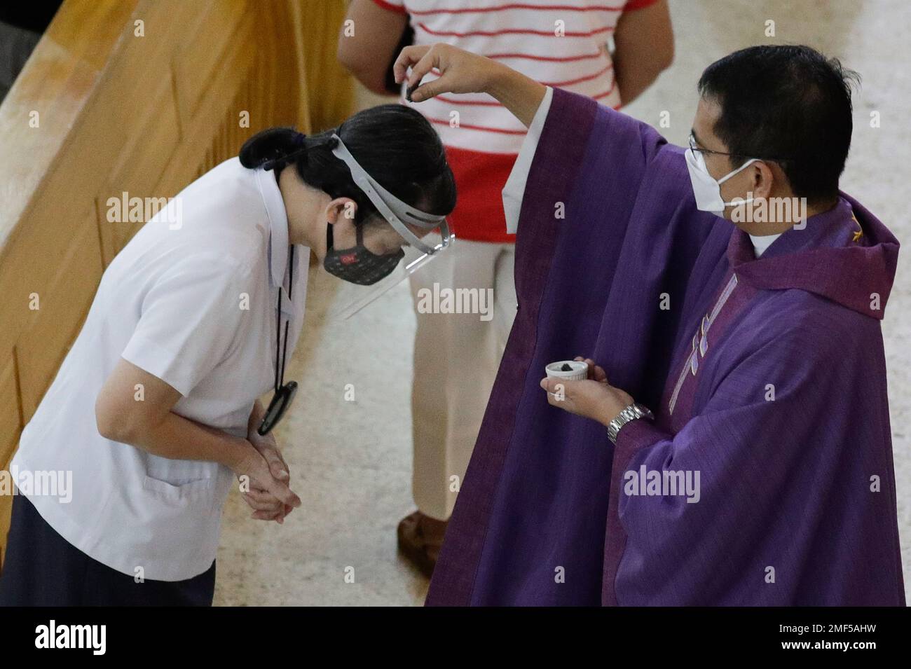 A Catholic priest sprinkles ash on the head of a devotee during Ash ...