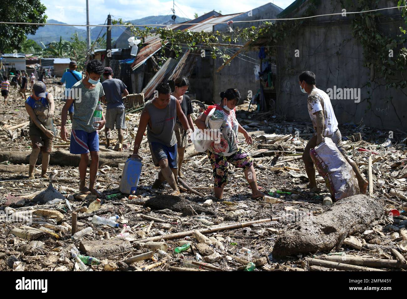 Residents walk through mud and debris at the typhoon-damaged Kasiglahan ...