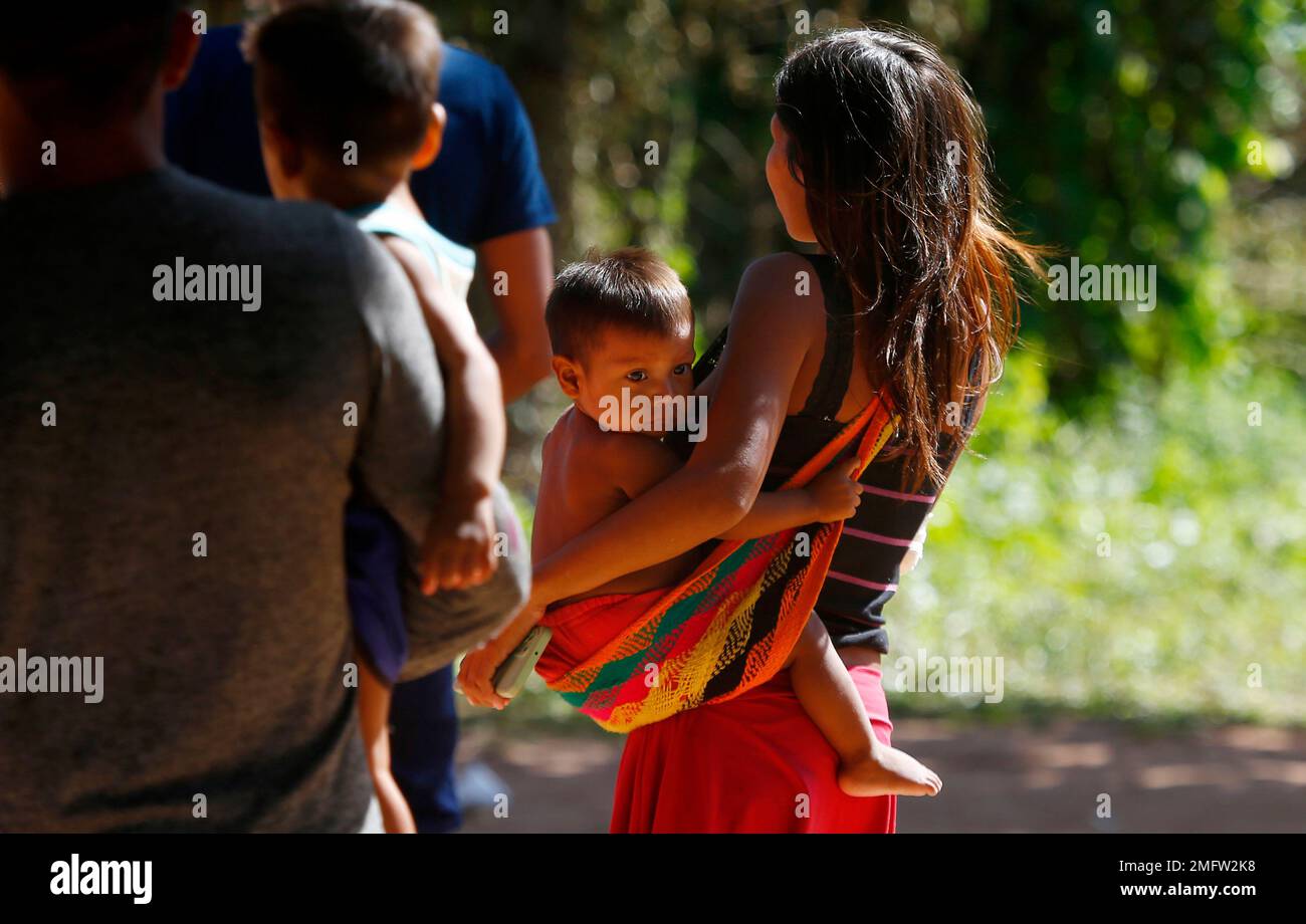 A Yanomami woman carries a toddler on the property of the Saude ...