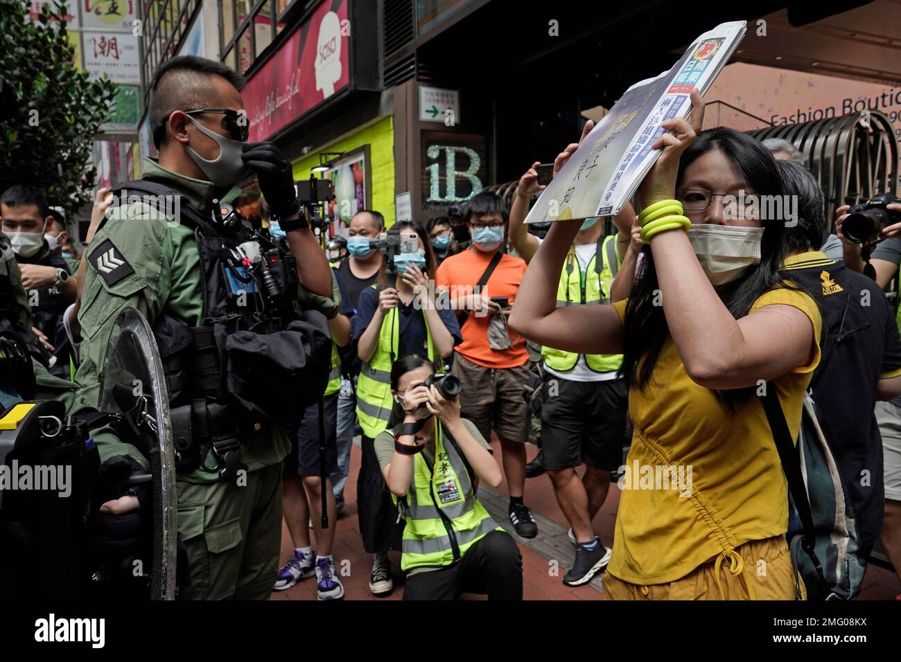 A protester shows a front page of Apple Daily to riot police to demand ...