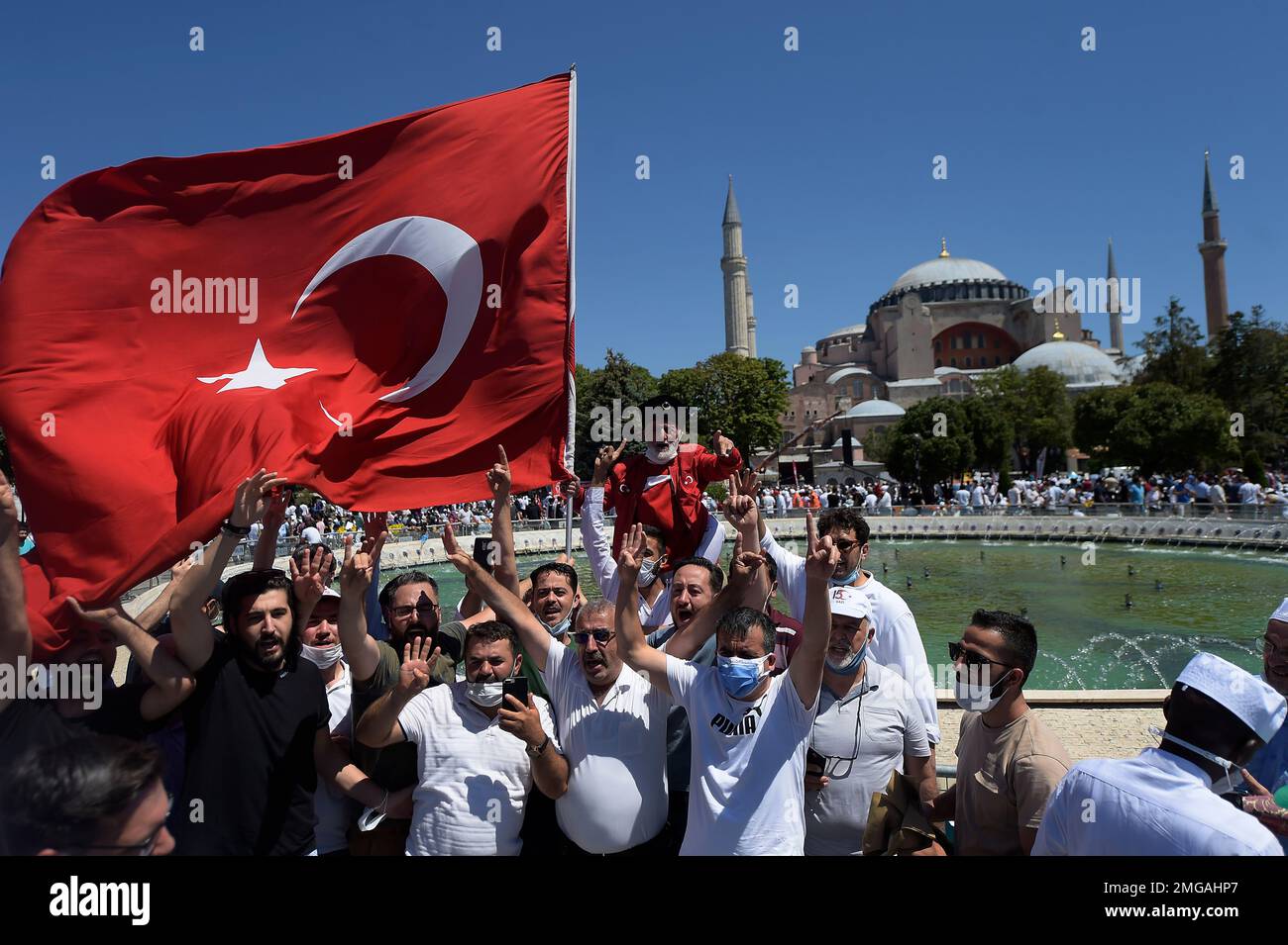 Faithful, one holding a Turkish flag, chant slogans as they wait at the ...