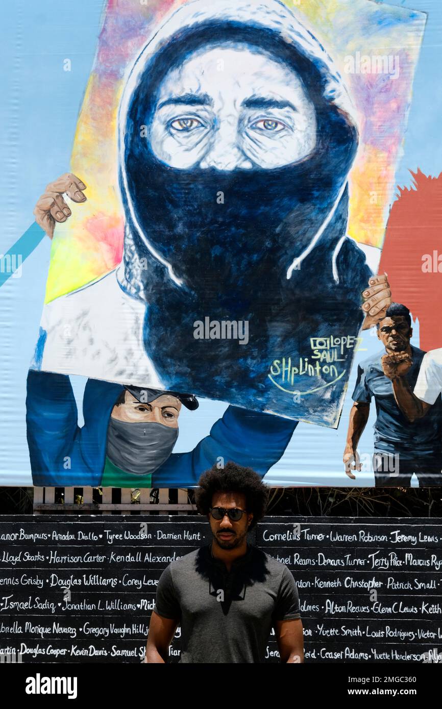 An artist who goes by the name Shplinton stands by a section of a mural ...