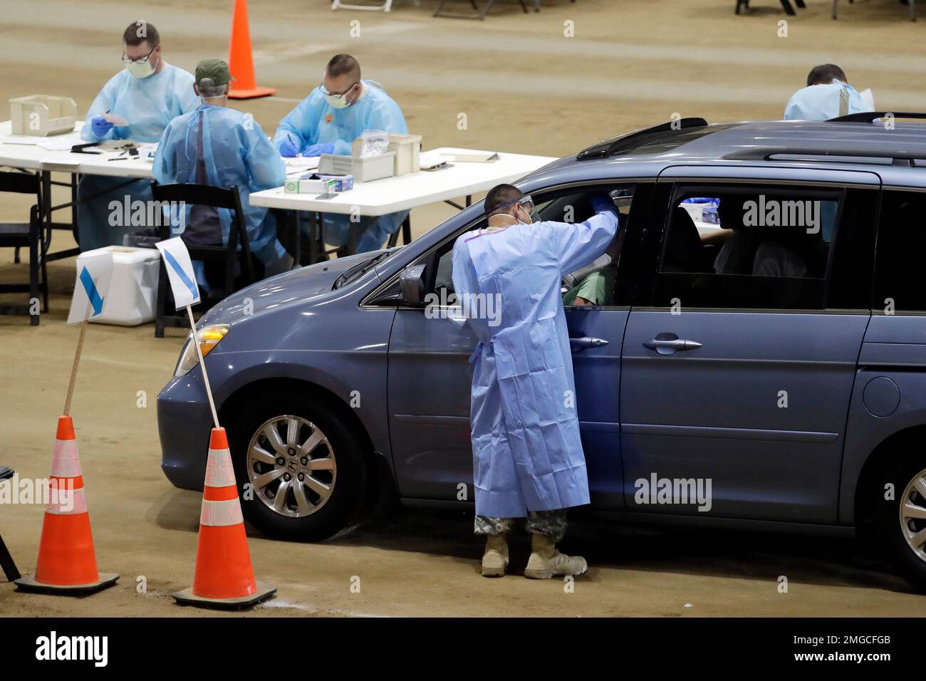 Workers administer COVID-19 tests at a drive-through facility set up in ...