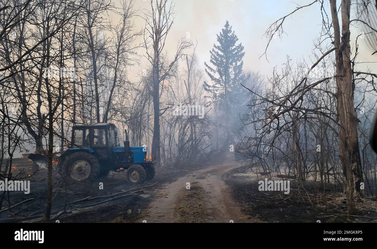 Chernobyl zone workers extinguish a forest fire burning near the ...