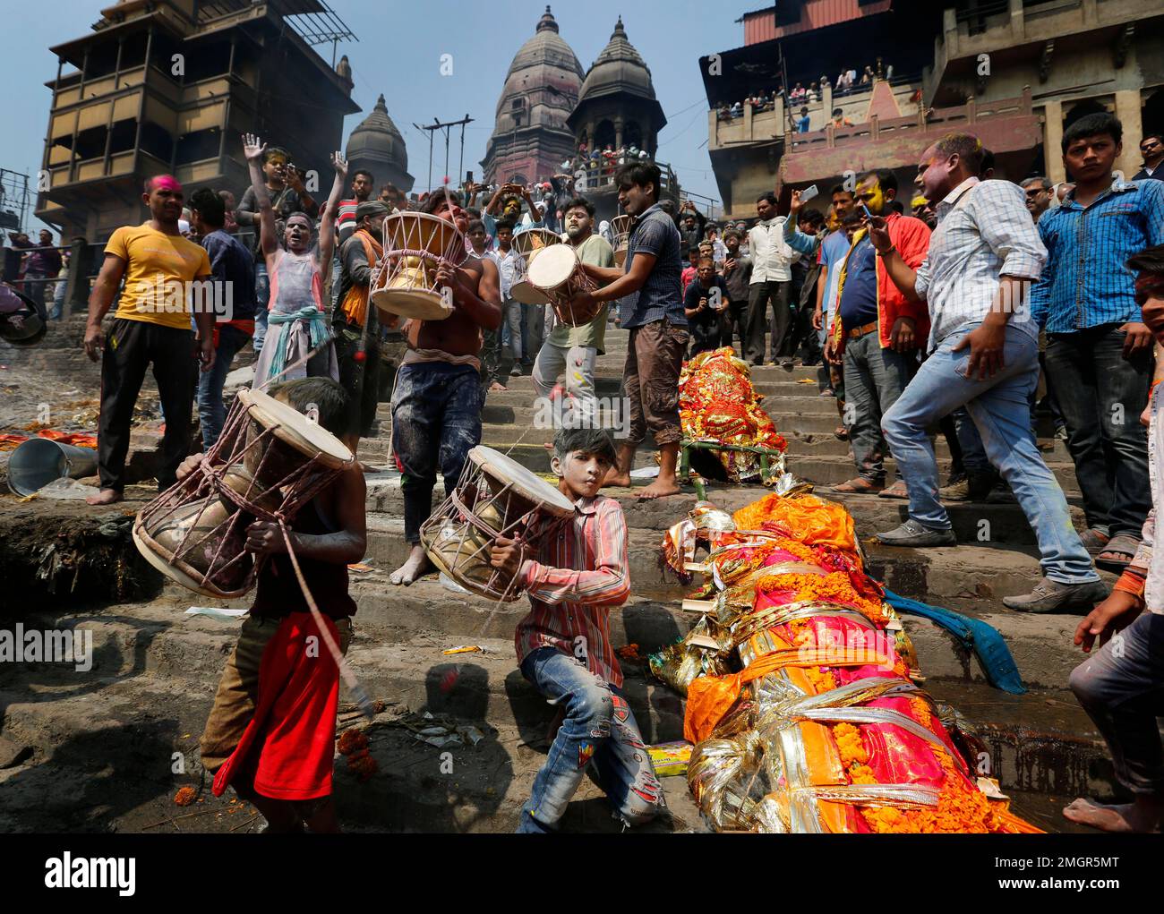 Devotees hold drums next to the covered dead bodies before their ...