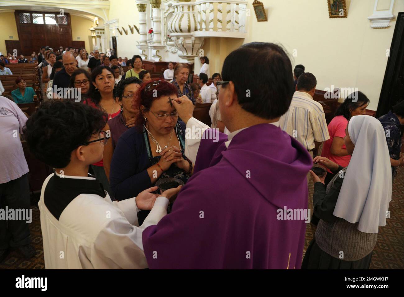 A priest marks the forehead of a woman with the symbol of the cross ...