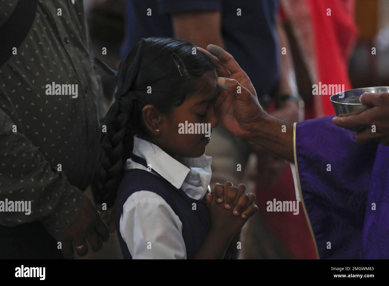 A Catholic priest marks the forehead of a girl with the symbol of a ...