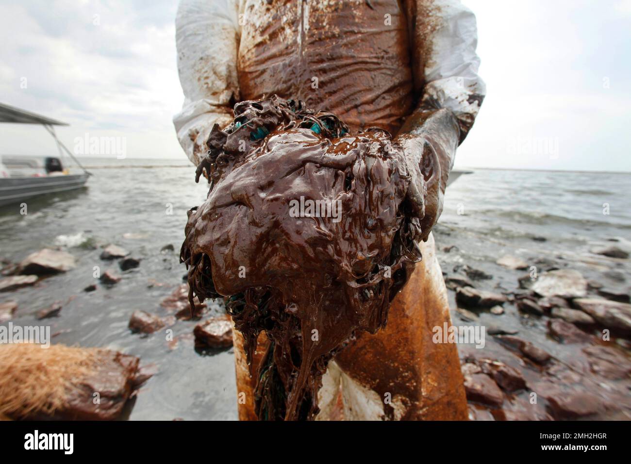 FILE - In this June 4, 2010, file photo, a cleanup worker picks up ...