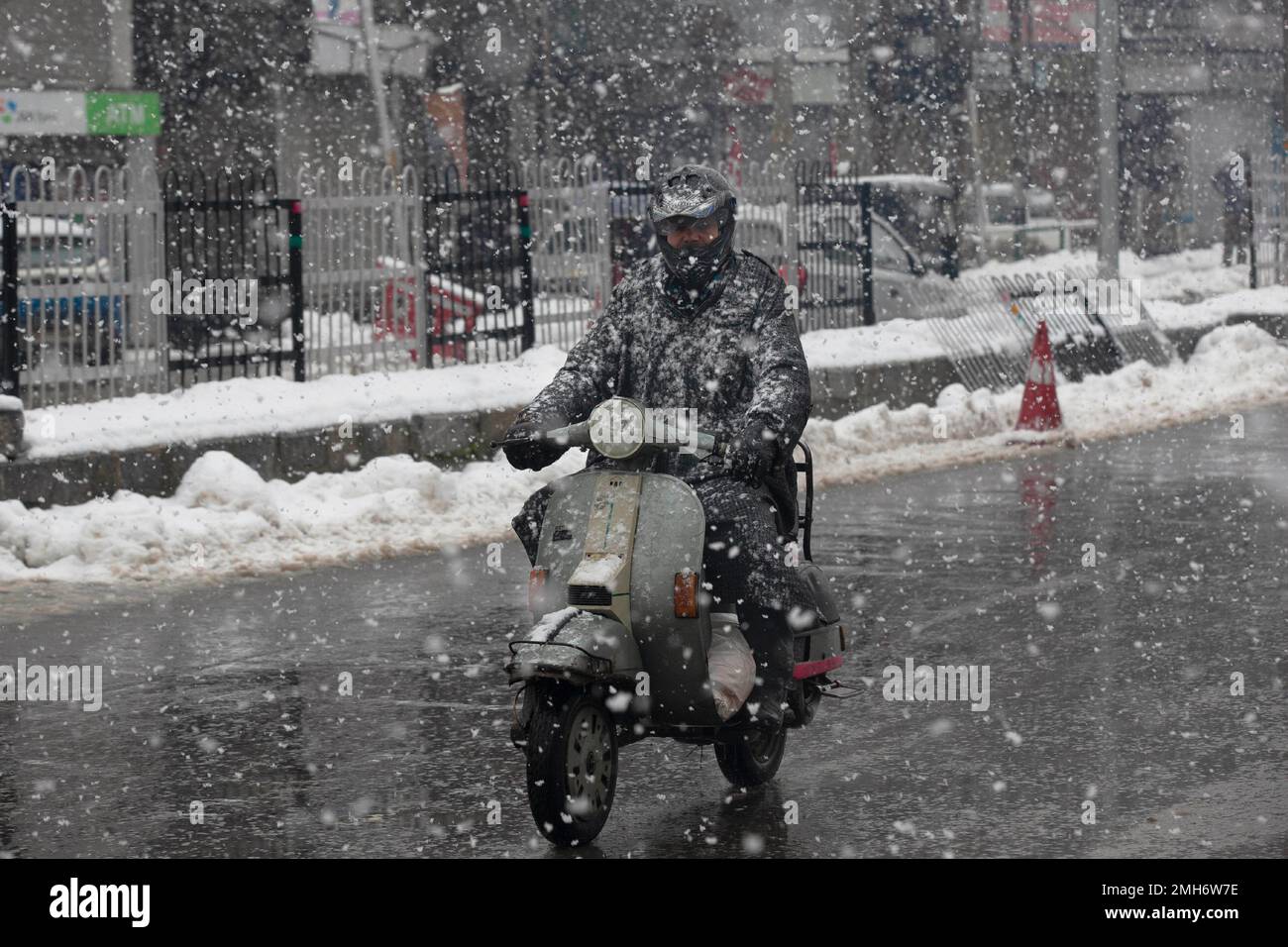 A Kashmiri man drives a scooter as snow falls in Srinagar, Indian ...