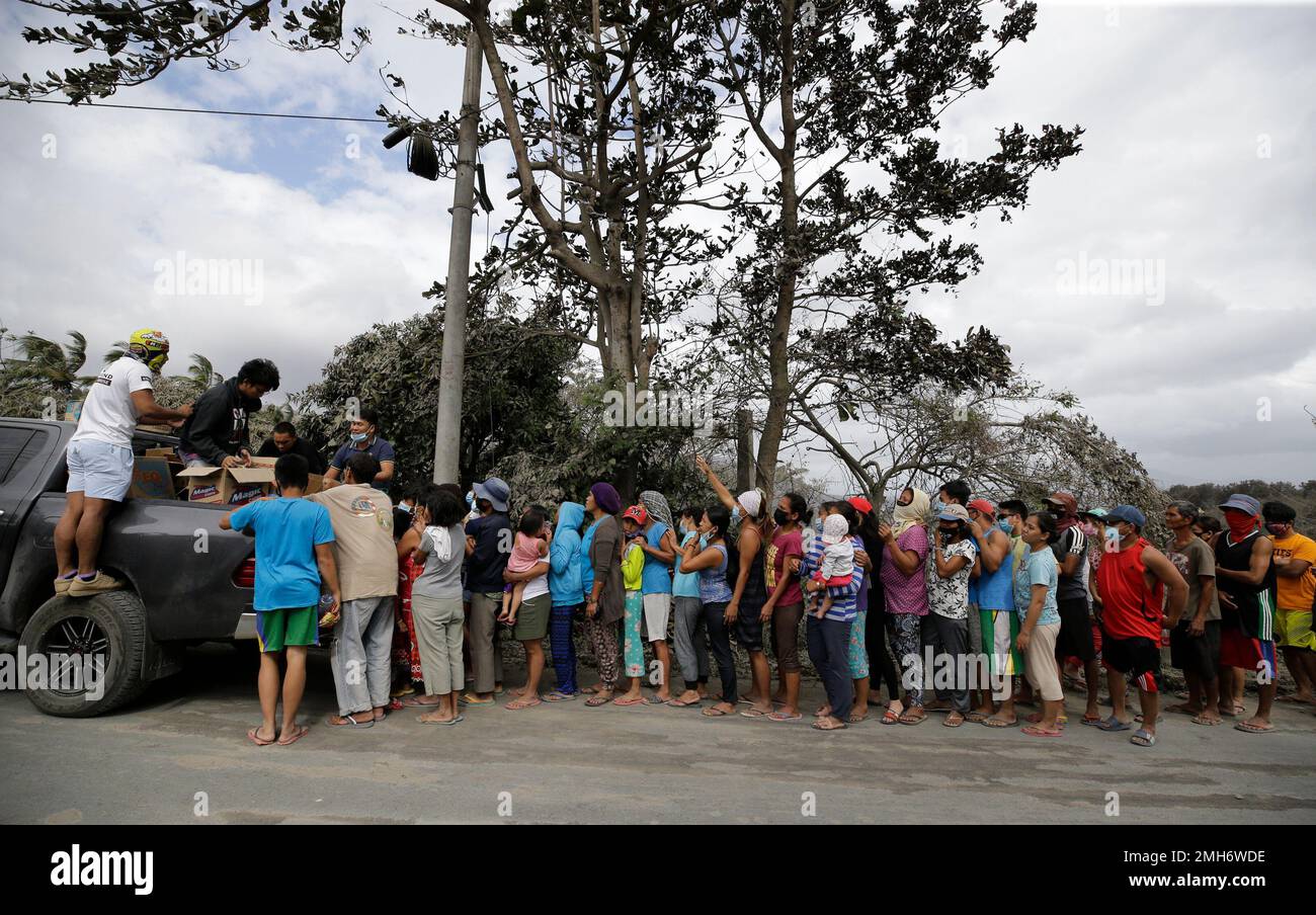 Residents living along the ridge overlooking Taal volcano line up for ...