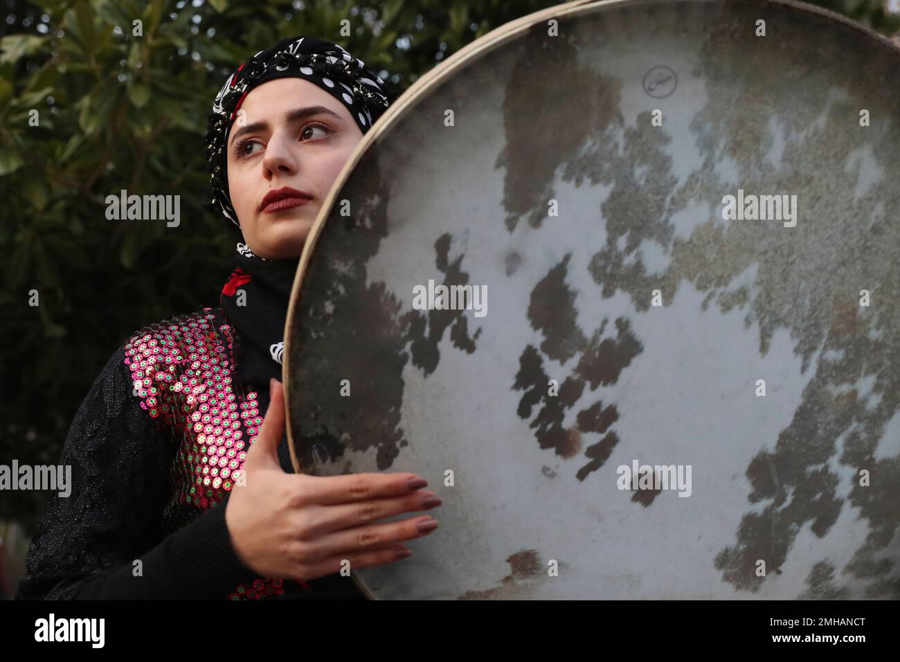 An Iranian Kurd musician in traditional attire plays a Daf, a hand-held ...