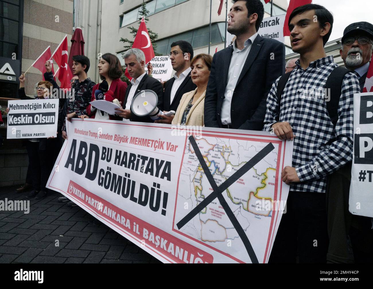 Members of a Turkish political party hold national flags and a banner ...