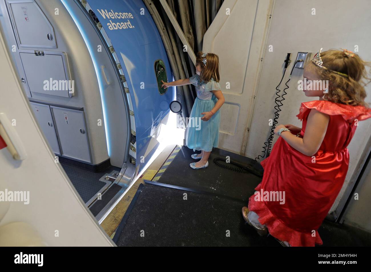 Two passengers dressed as Disney princesses react as they spot Rex, a ...