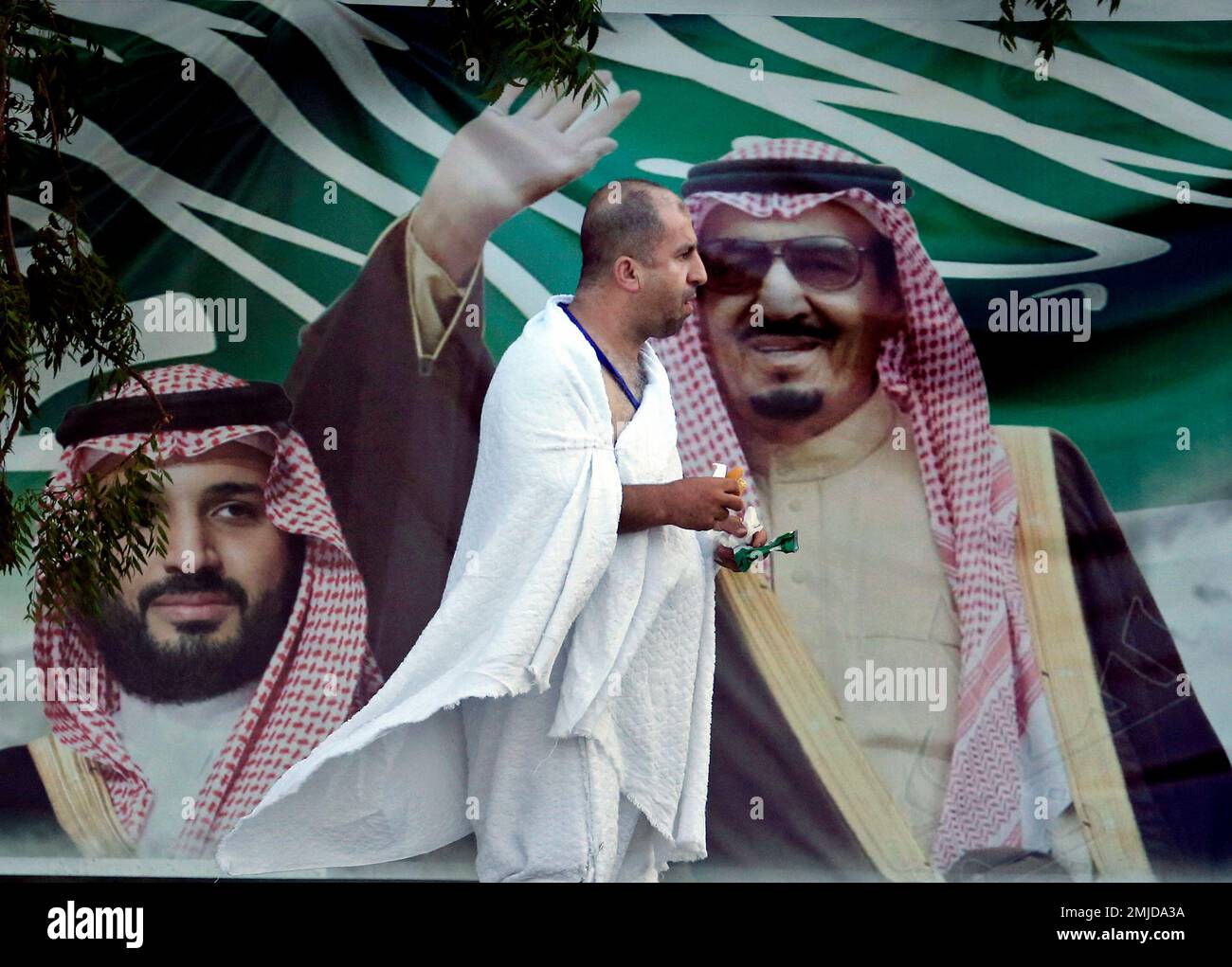 A Lebanese pilgrim walks in front of a banner showing Saudi King Salman ...
