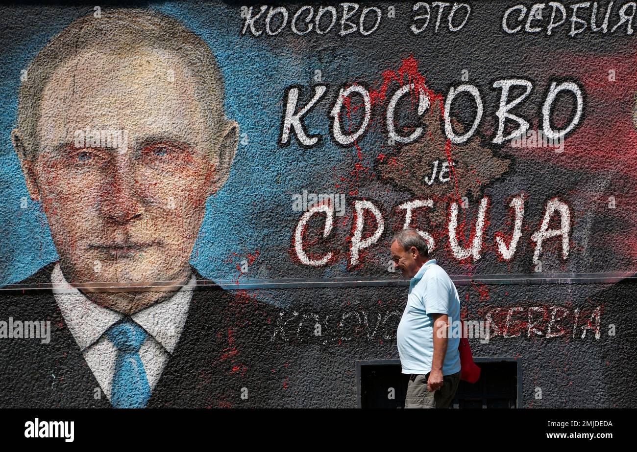 A man passes by graffiti depicting the Russian President Vladimir Putin ...