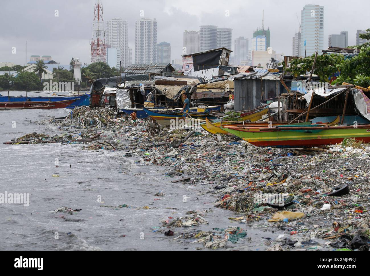 A resident looks as garbage that is washed ashore by strong waves piles ...
