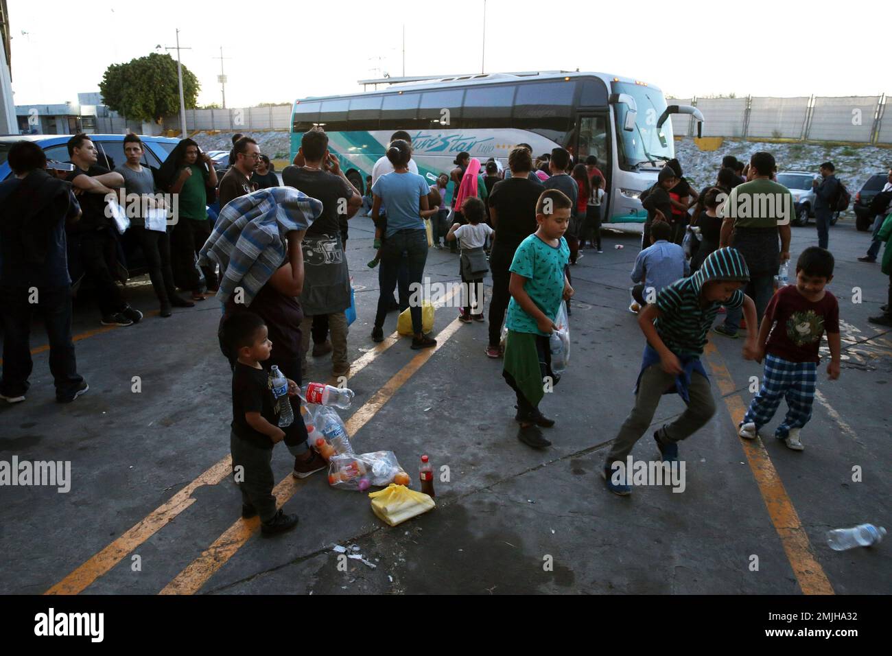 Migrants wait outside at an immigration center on the International ...