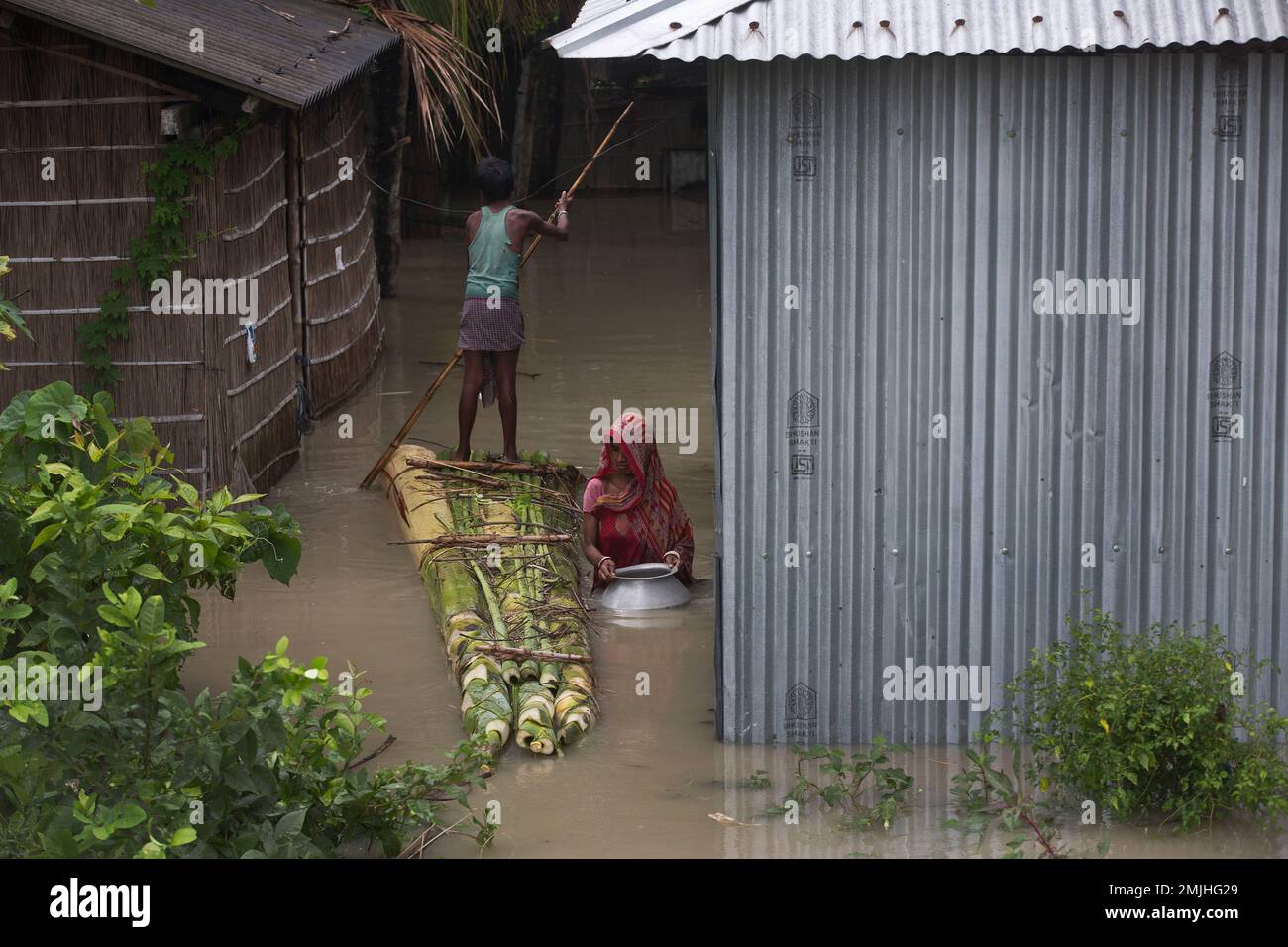 An Indian flood affected woman carries drinking water as a boy rows a ...