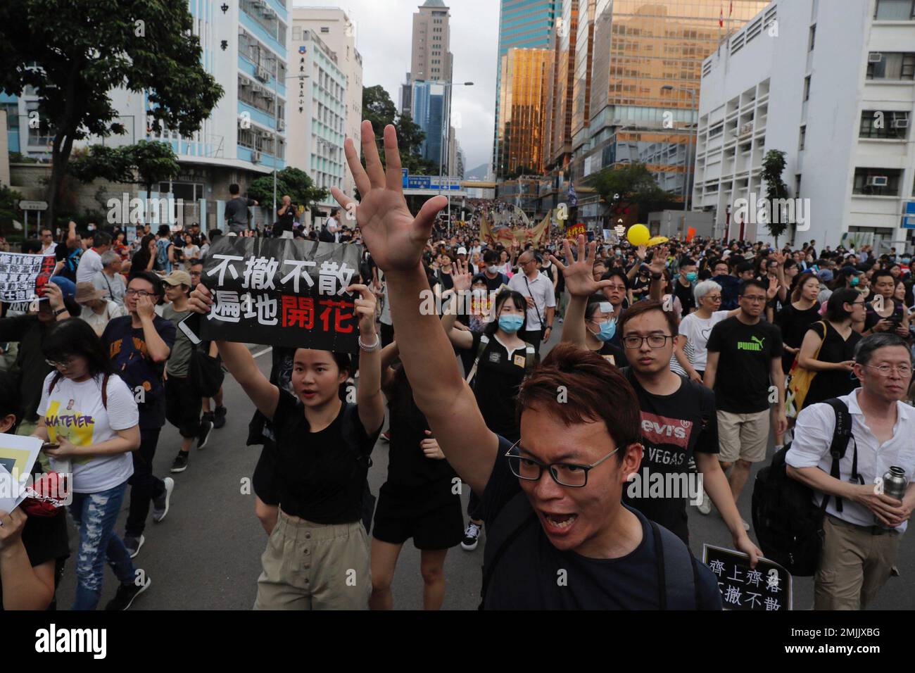 Protesters hold up five fingers to represent the five demands they have ...