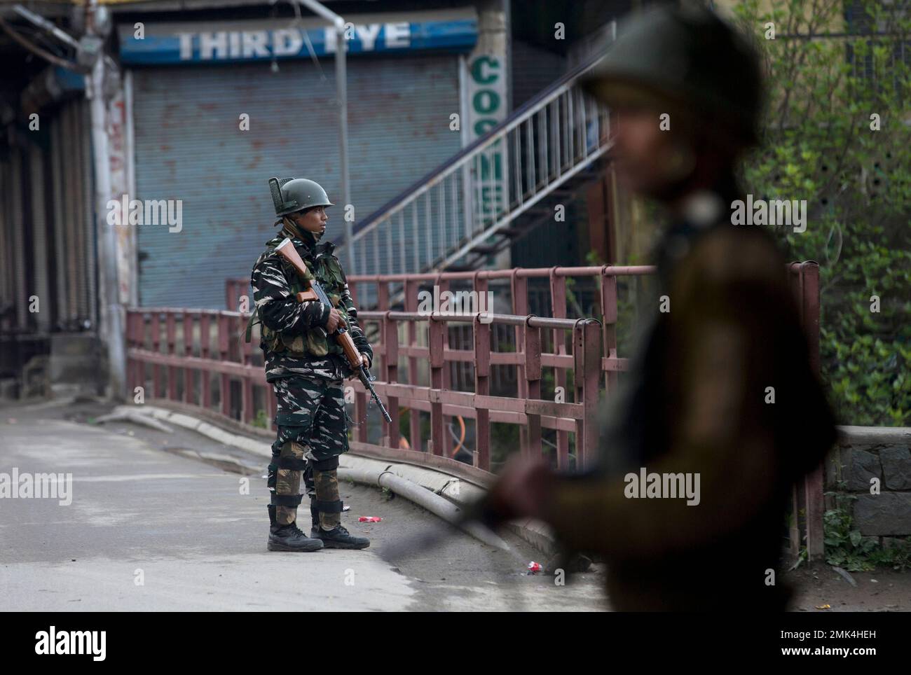 Indian paramilitary soldiers stand guard on a deserted street during ...