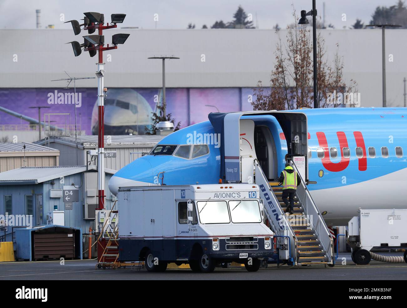 A worker walks up steps to the right of an avionics truck parked next ...