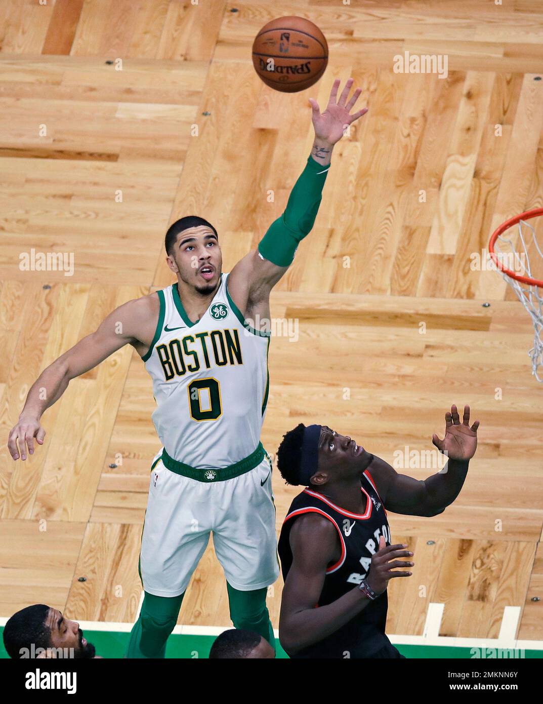 Boston Celtics forward Jayson Tatum (0) reaches for a rebound over Toronto Raptors forward ...