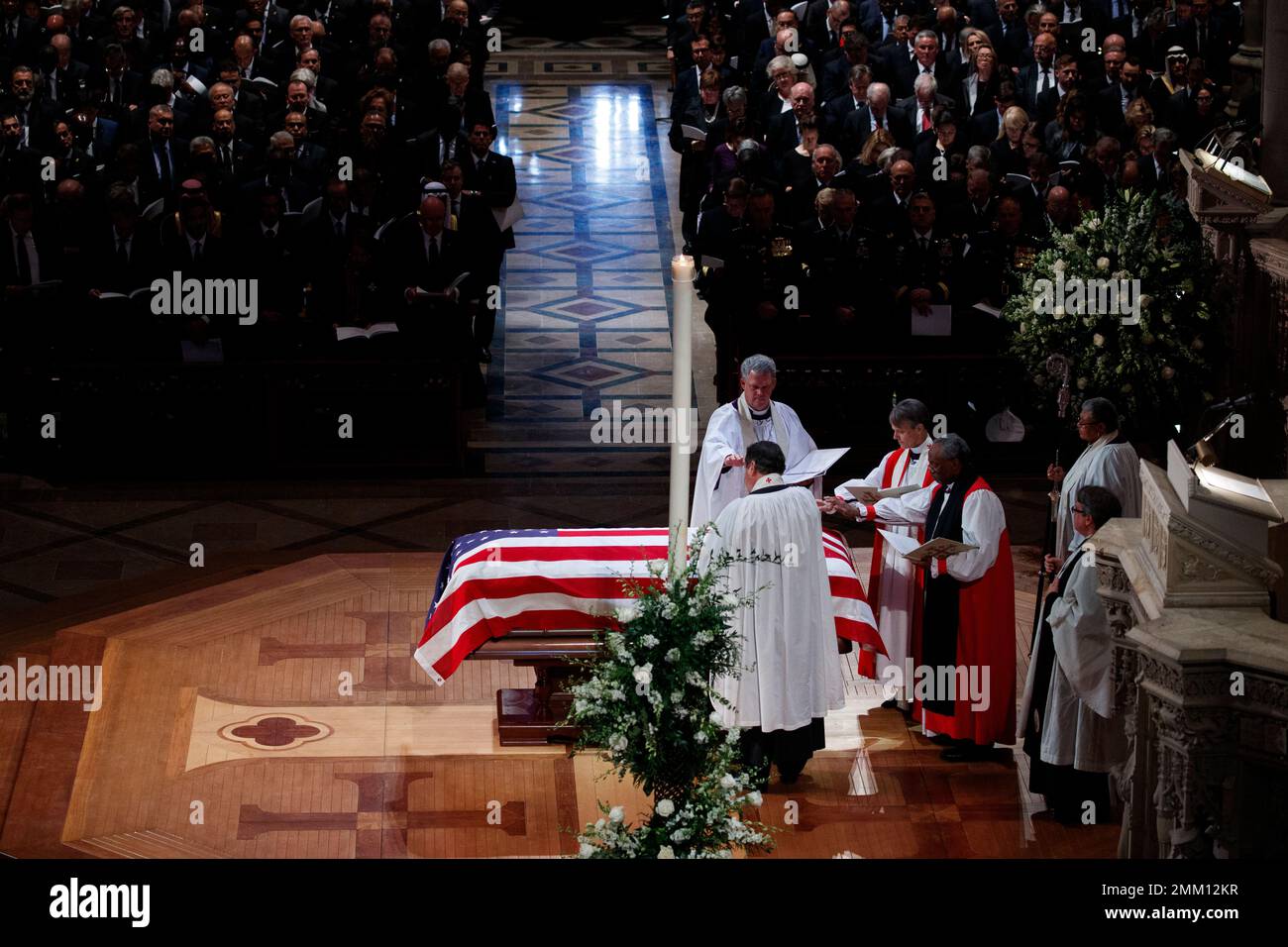 Members of the clergy put their hands over the flag-draped casket of ...