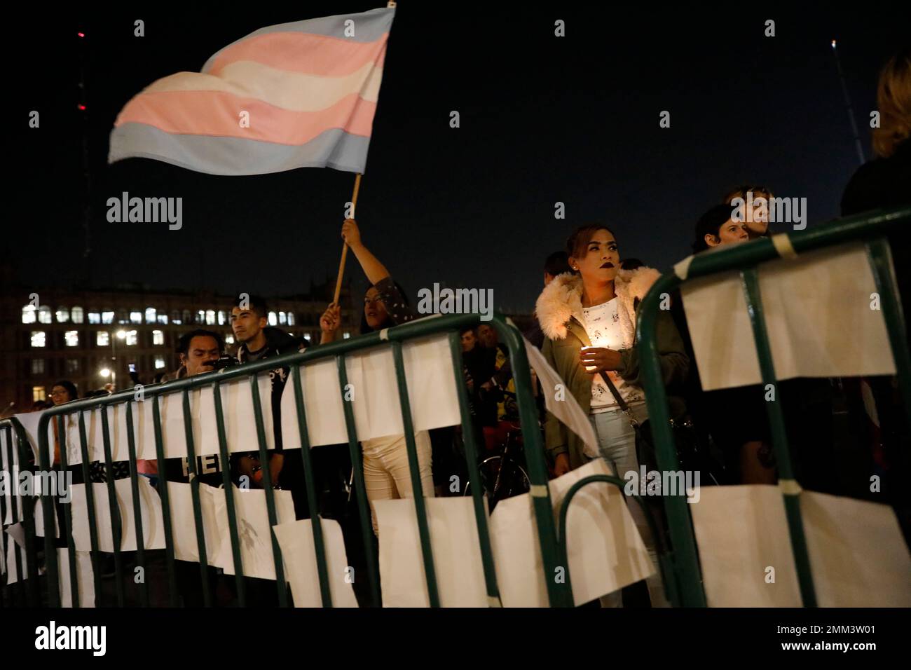 Luna Nolasco holds a candle in front of signs bearing the names of 100 ...