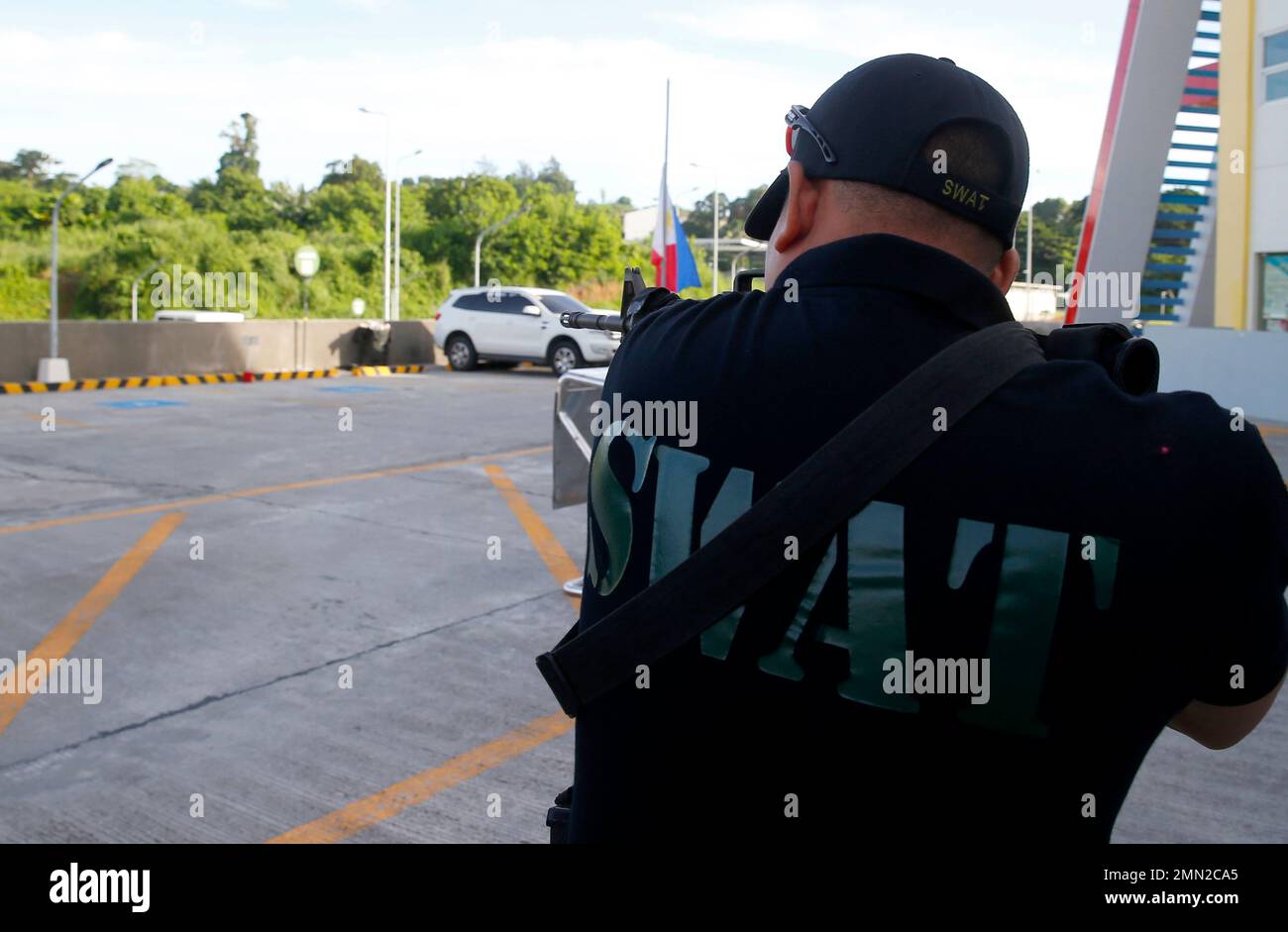 Philippine National Police SWAT member aims his rifle to check a site ...