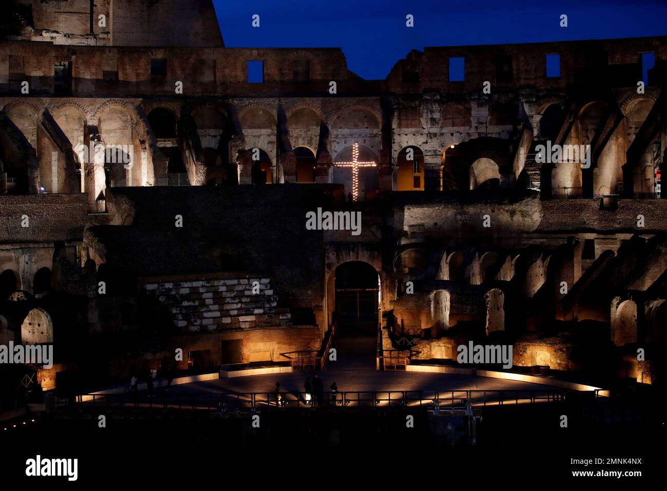 A torchlit crucifix is framed by the arches of the Rome's ancient ...