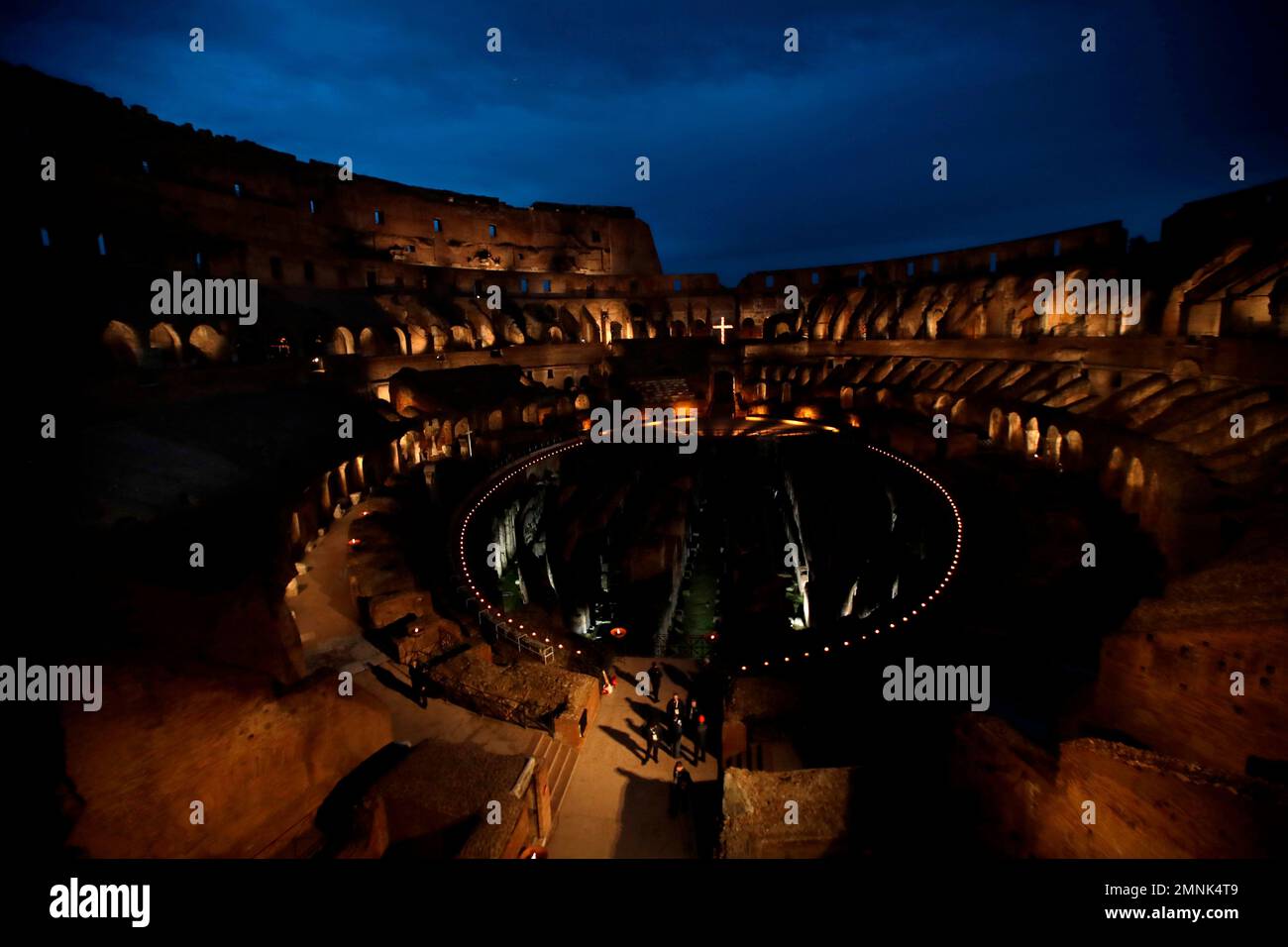 A torchlit crucifix is framed by the arches of the Rome's ancient ...