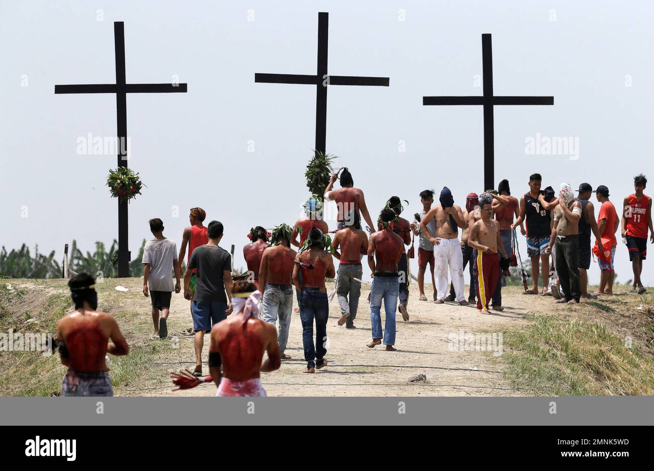 Filipino hooded penitents walk towards crosses during Good Friday ...