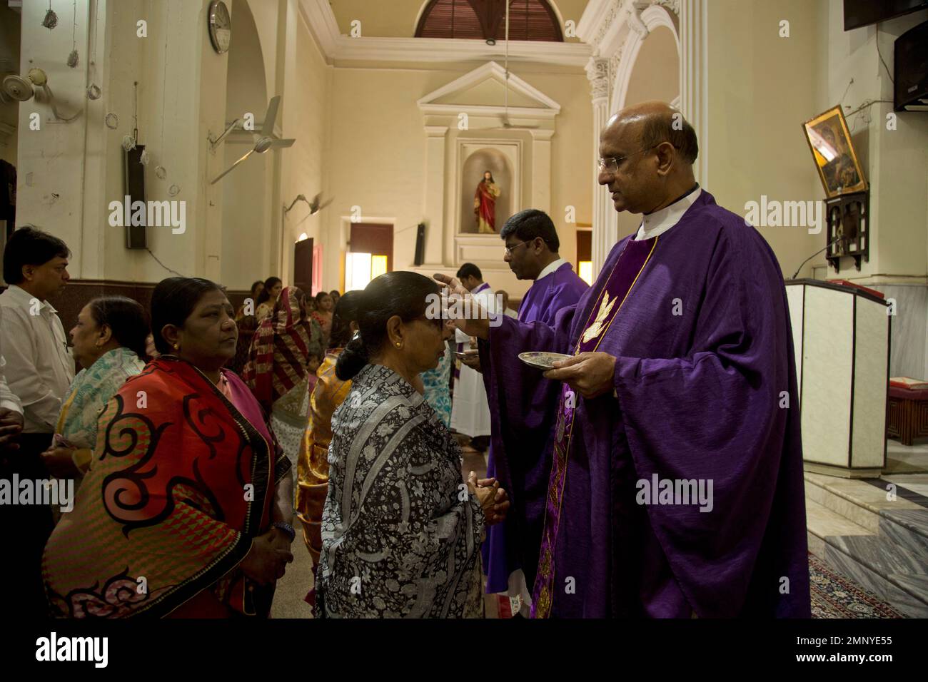 An Indian Catholic priest marks cross symbol on the forehead of ...