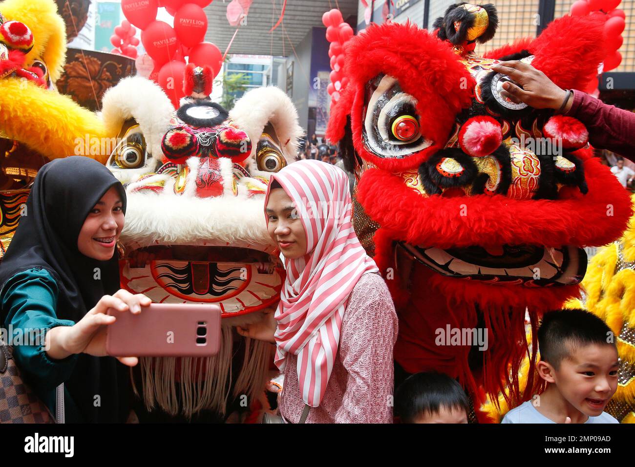 Muslims women take pictures with the lion dance at a shopping mall ...