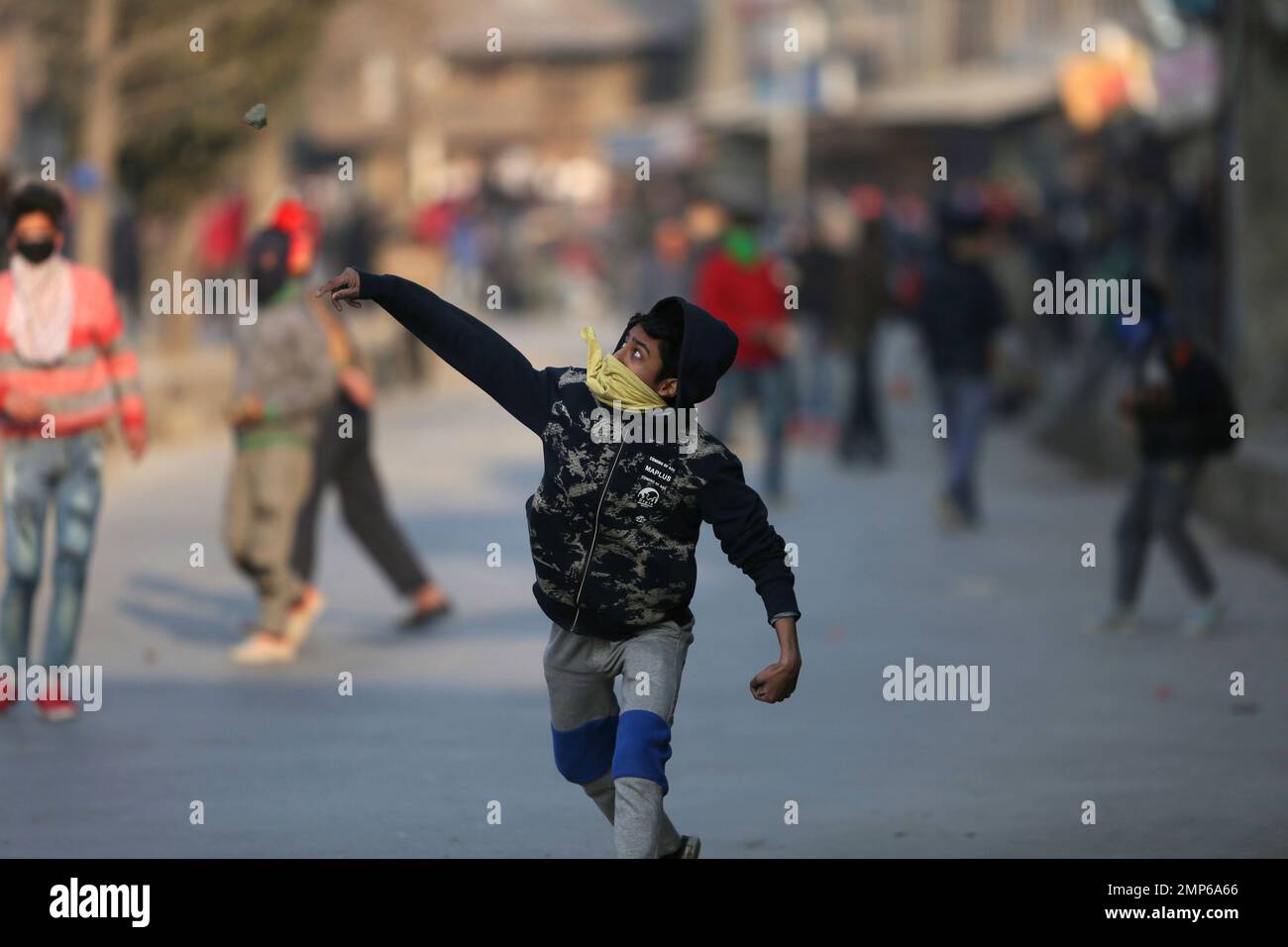 A masked Kashmiri protester throws stones on Indian policemen during a ...