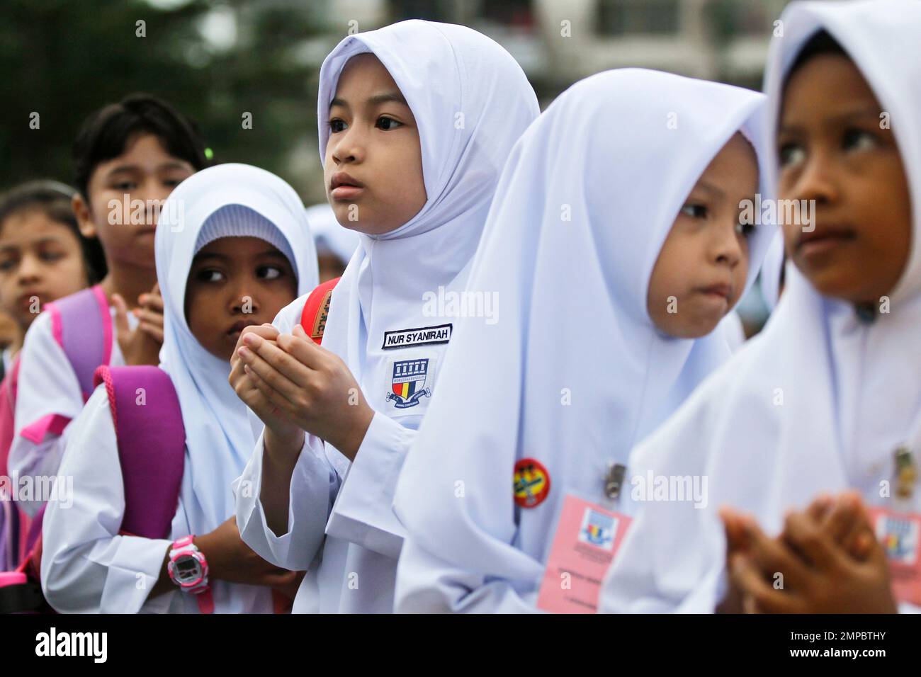 Primary school students pray during the first day of school sessions in ...