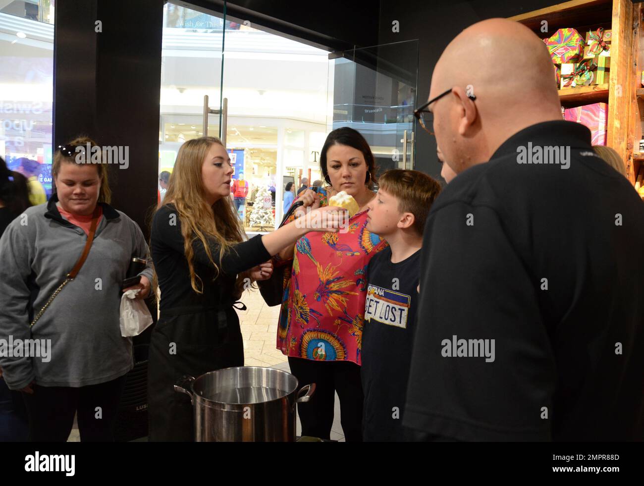 A sales attendant gives a soap demonstration to a group of shoppers at ...