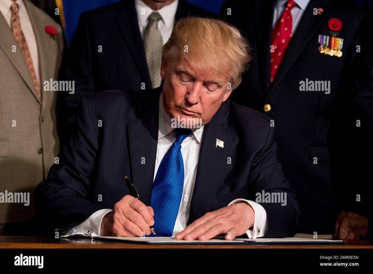 President Donald Trump, surrounded by Vietnam veterans, signs a ...