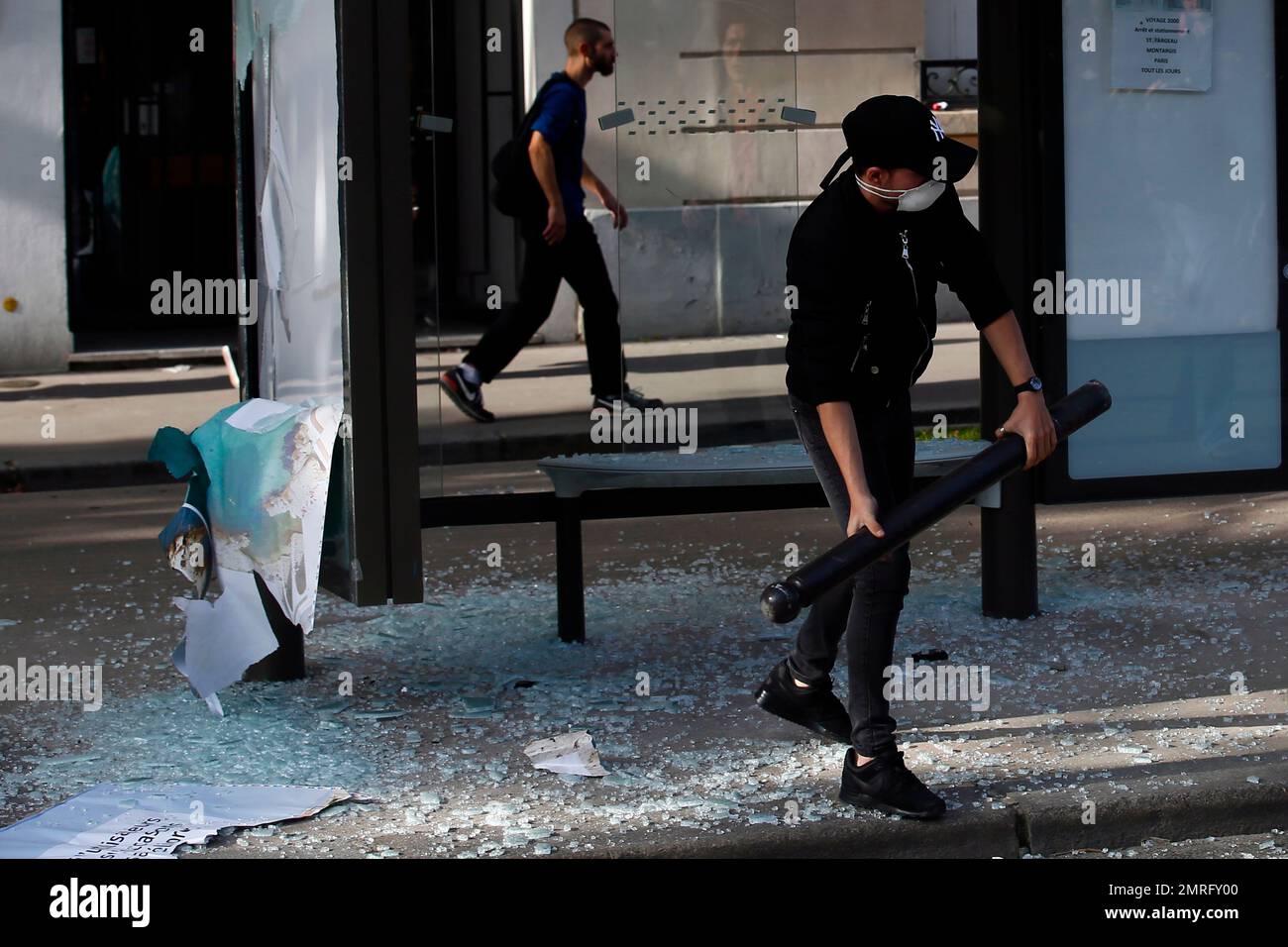 Masked protesters smash an advertising board during a protest march ...