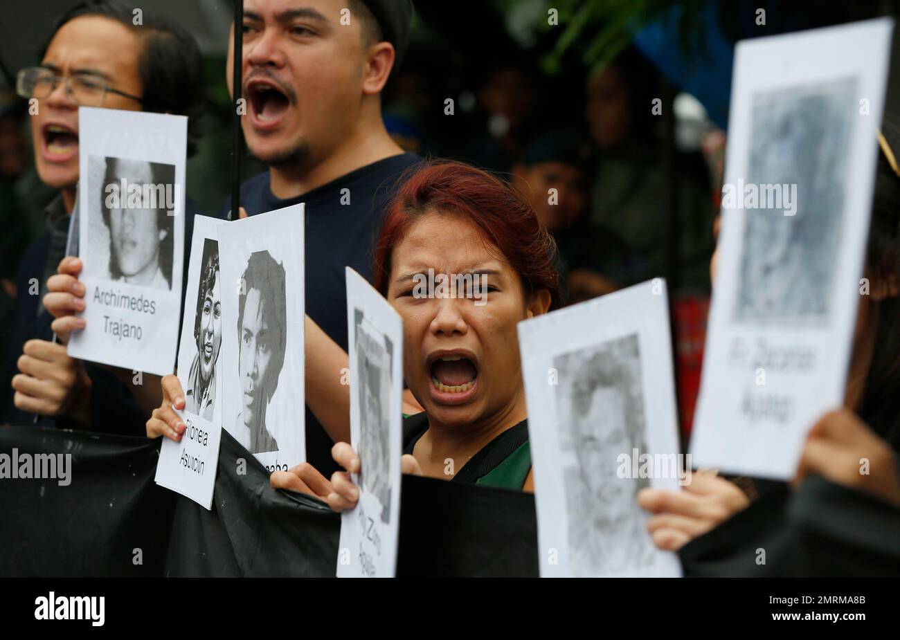 Protesters shout slogans while displaying portraits of alleged victims ...