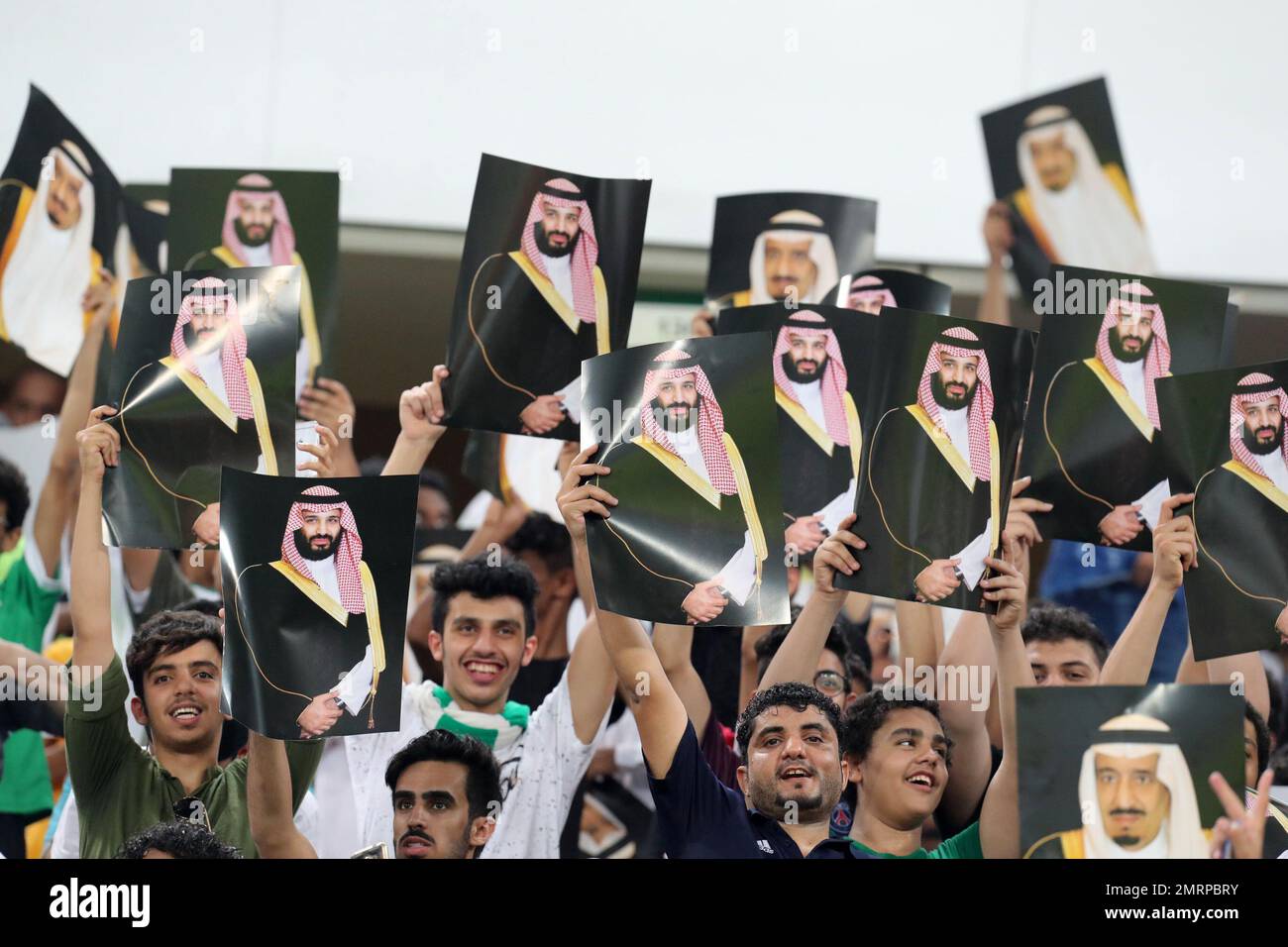 Saudi Arabia fans cheer as they hold up pictures of Saudi King Salman ...