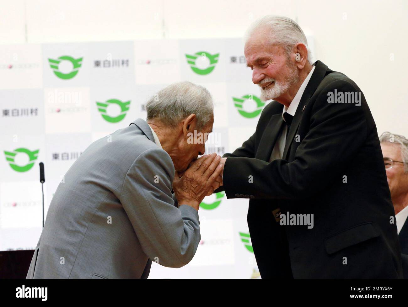 Tatsuya Yasue, left, kisses the hands of WWII veteran Marvin Strombo ...
