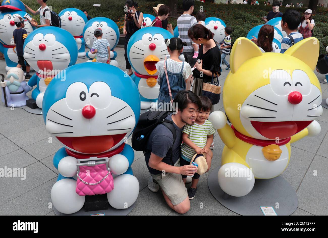 A father and a son pose for a photo with models of Doraemon, one of ...