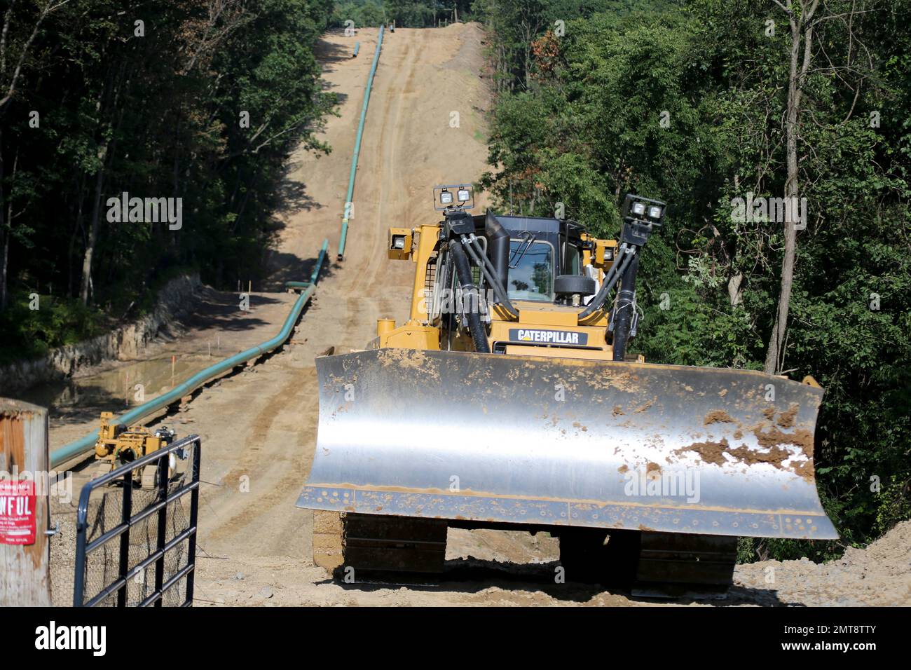 Segments of assembled pipe are lined up along a cleared section of ...