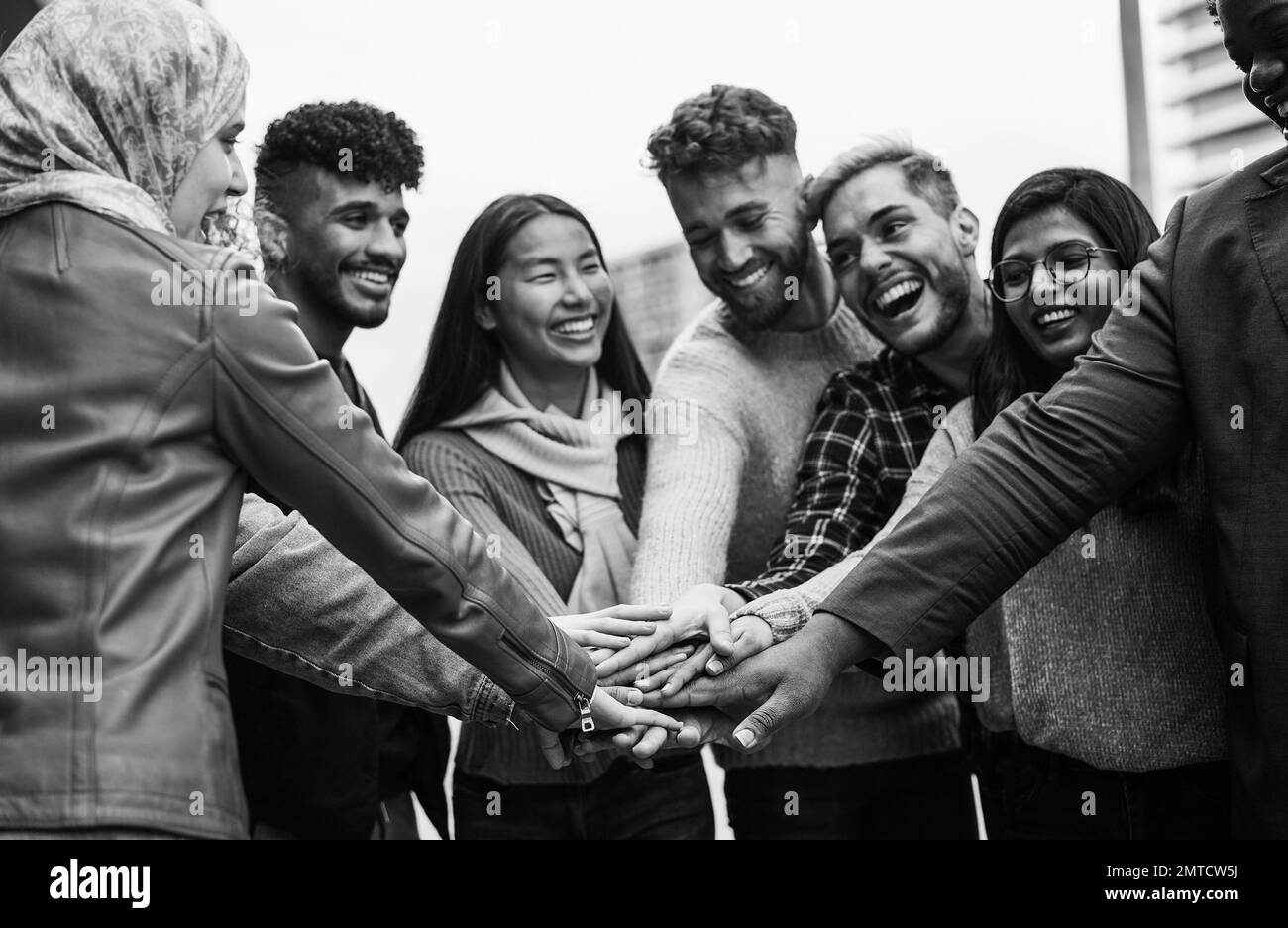 Junge, vielfältige Teams haben Spaß beim Stapeln von Händen im Freien ...